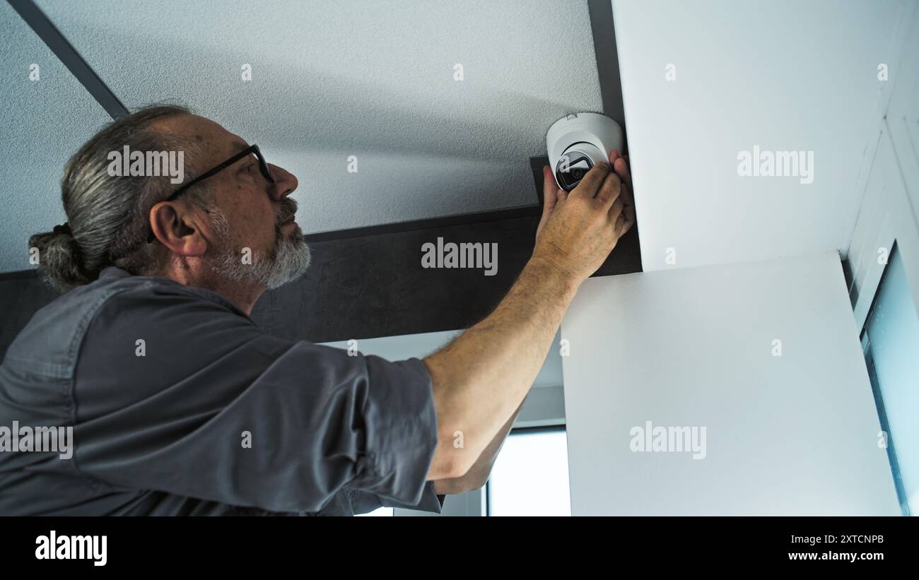 Professional male installer in uniform screws security camera to the ...