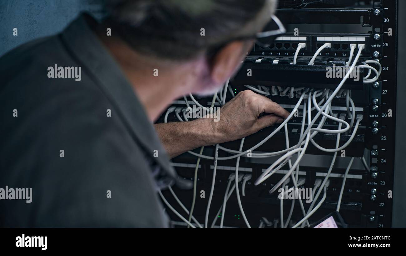 Mature specialist works in server room. Male network administrator ...