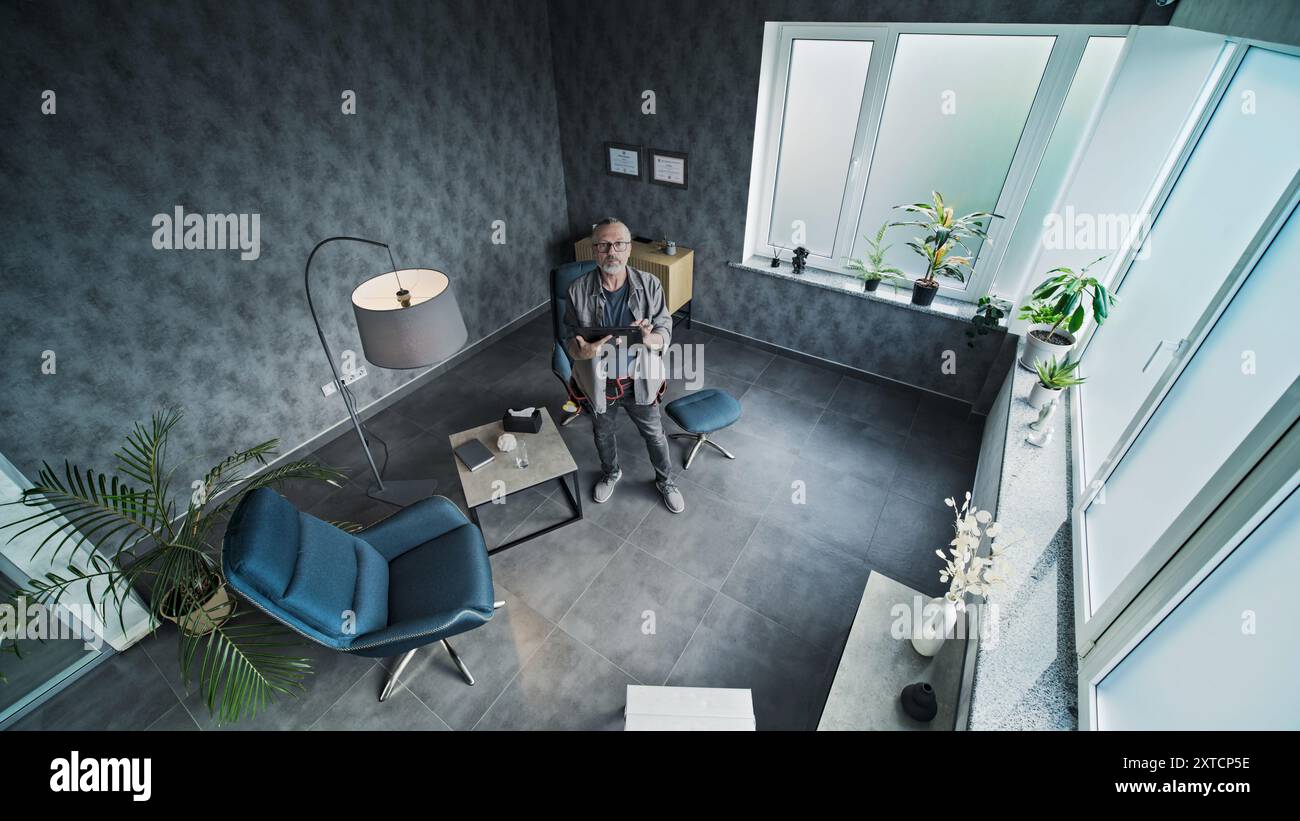 Male mature installer sets up angle of CCTV camera, uses tablet ...