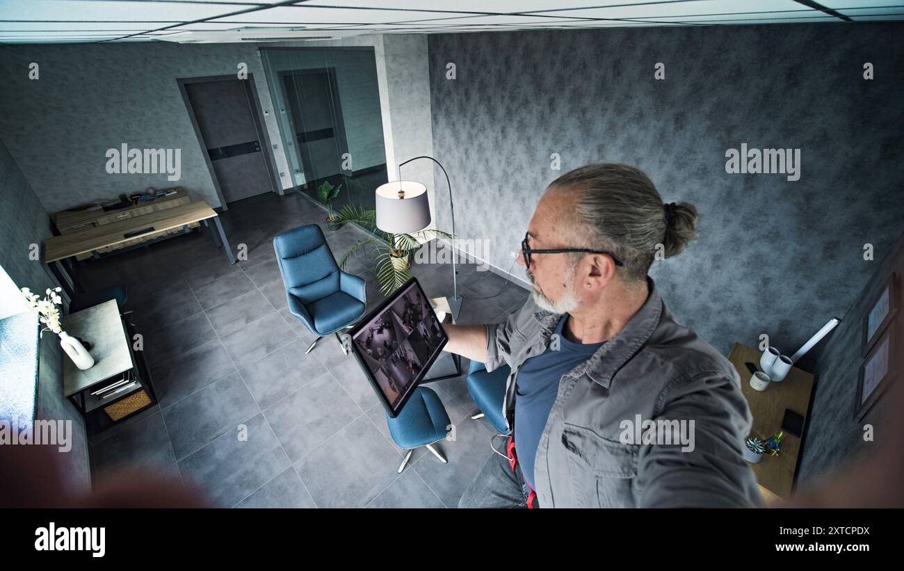 Male mature technician adjusts angle of CCTV camera, uses tablet ...