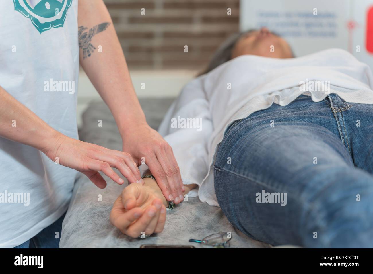 Nurse taking pulse of a woman lying on the stretcher Stock Photo - Alamy