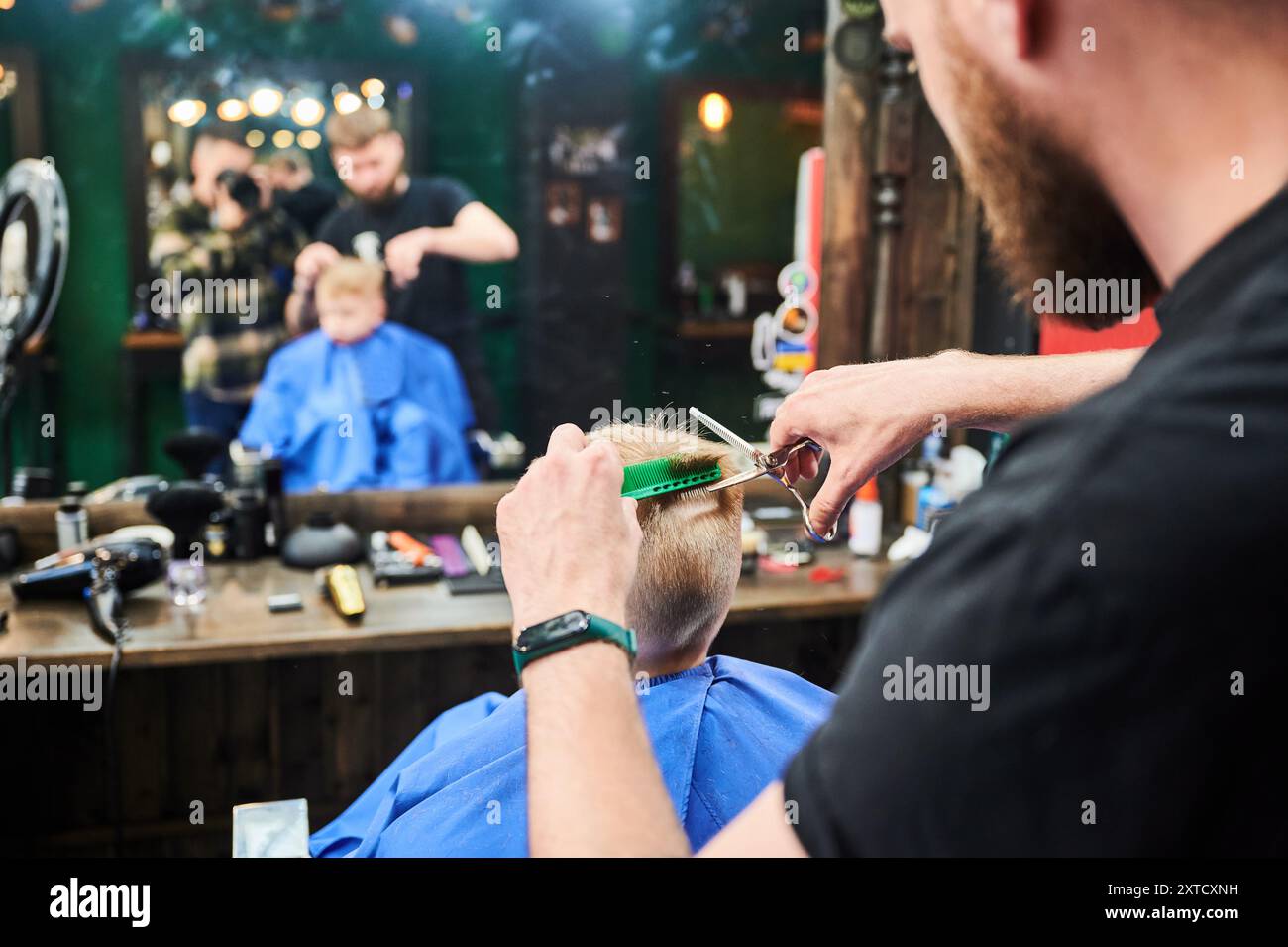 Behind shoulder view of male barber cutting little boy's hair. Young ...