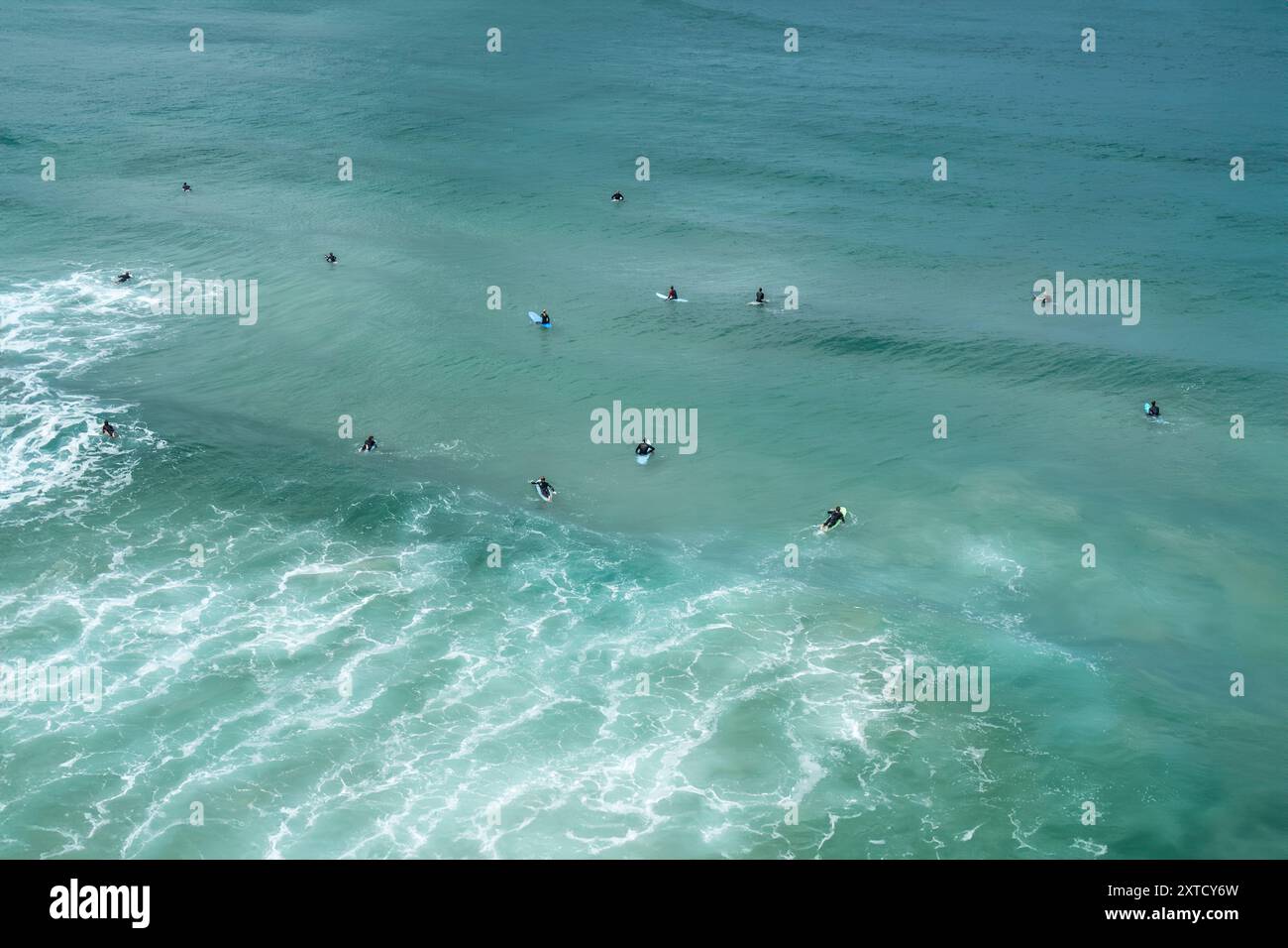An aerial view of surfers floating in the sea waiting for a wave on the ...
