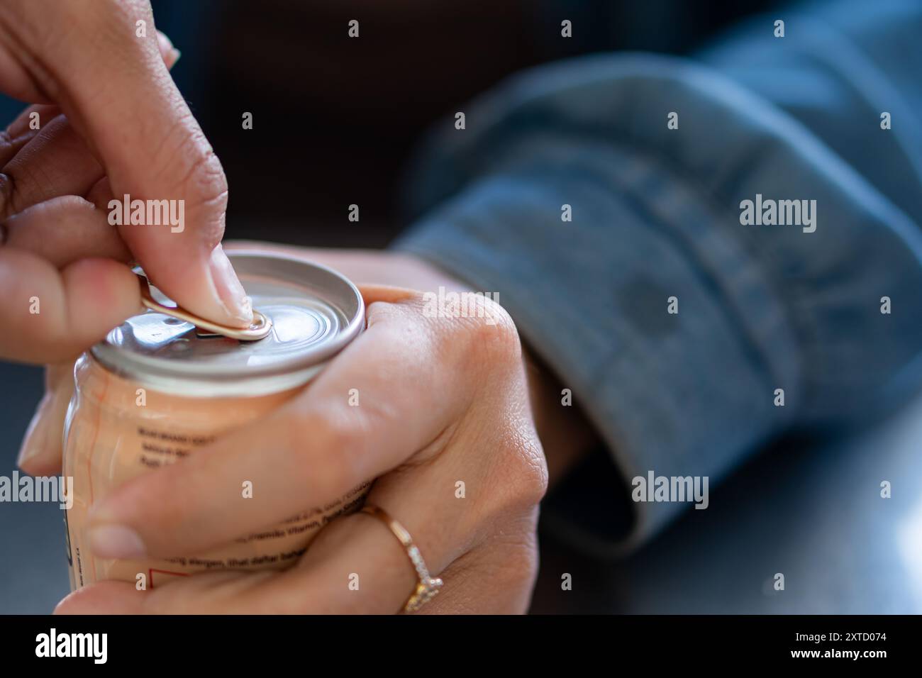 A close-up of a person's hands opening a soda can. The focus is on the ...