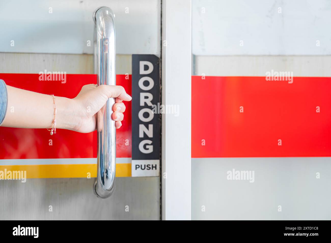 A close-up of a hand gripping a metallic door handle with a sign that ...