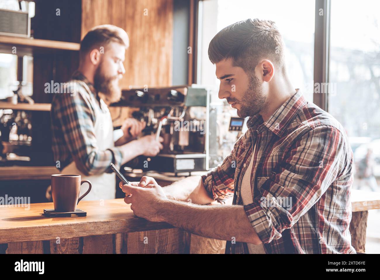 Spending time at coffee shop. Side view of young handsome man using his ...