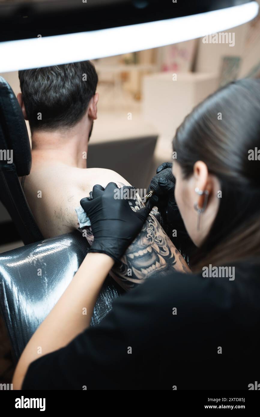professional woman artist making stylish black tattoo of Japanese demon ...
