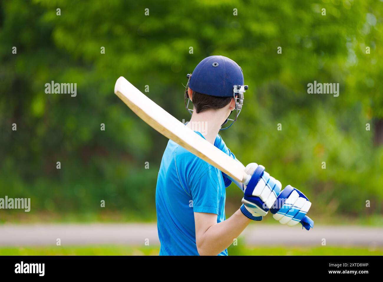 Young man playing cricket in summer park. Teenager with bat and ball on ...