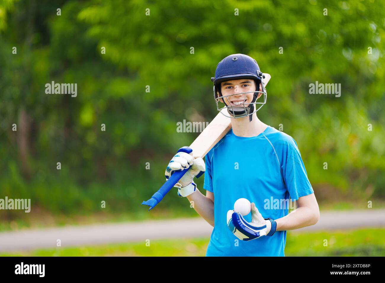 Young man playing cricket in summer park. Teenager with bat and ball on ...
