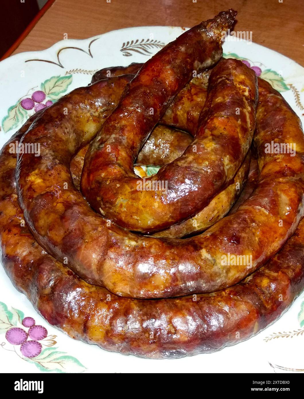 A beautifully baked organic meat sausage, coiled and resting on a ...