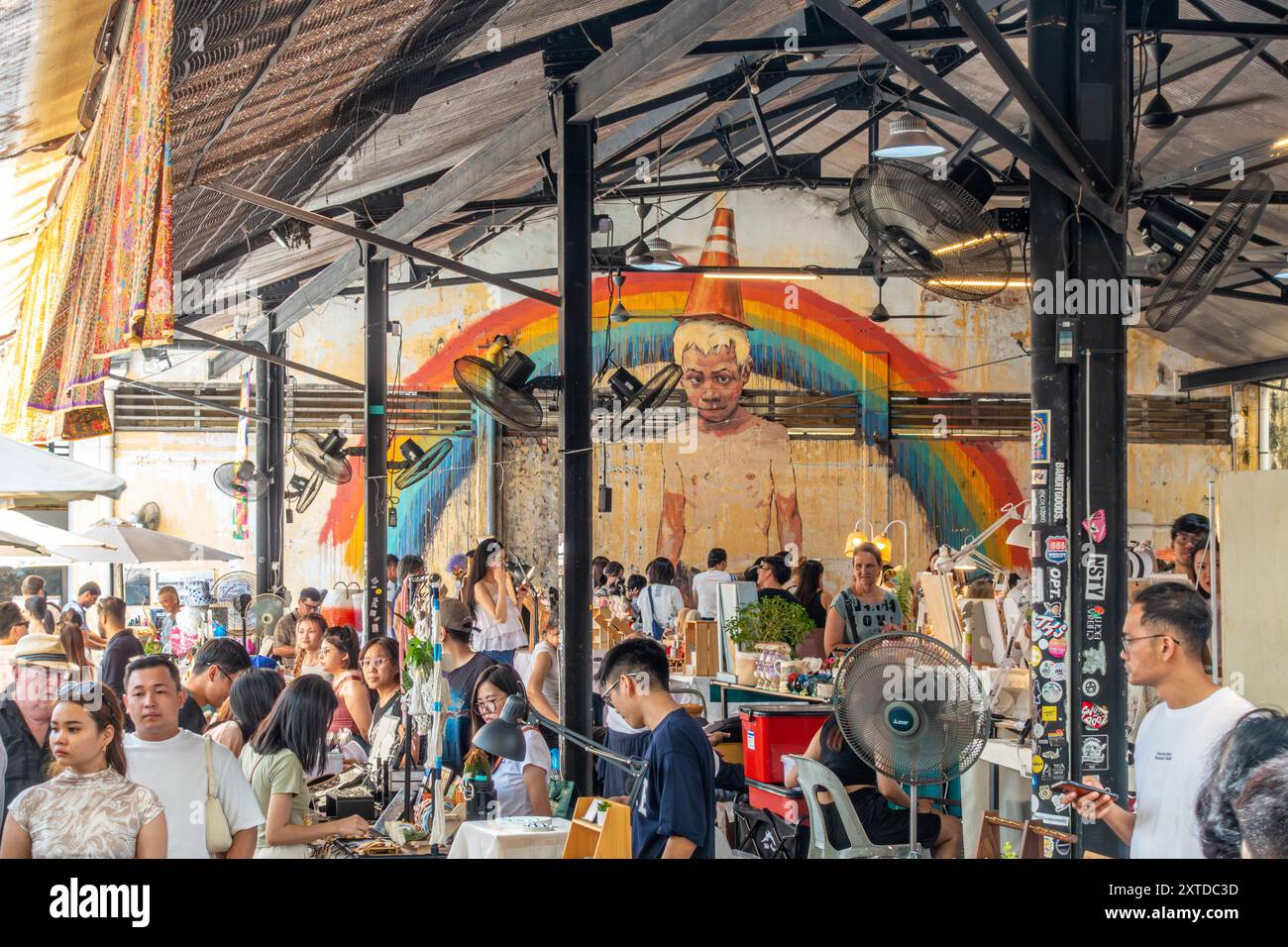 A mural of a boy with a cone on his head looks down on shoppers at the ...