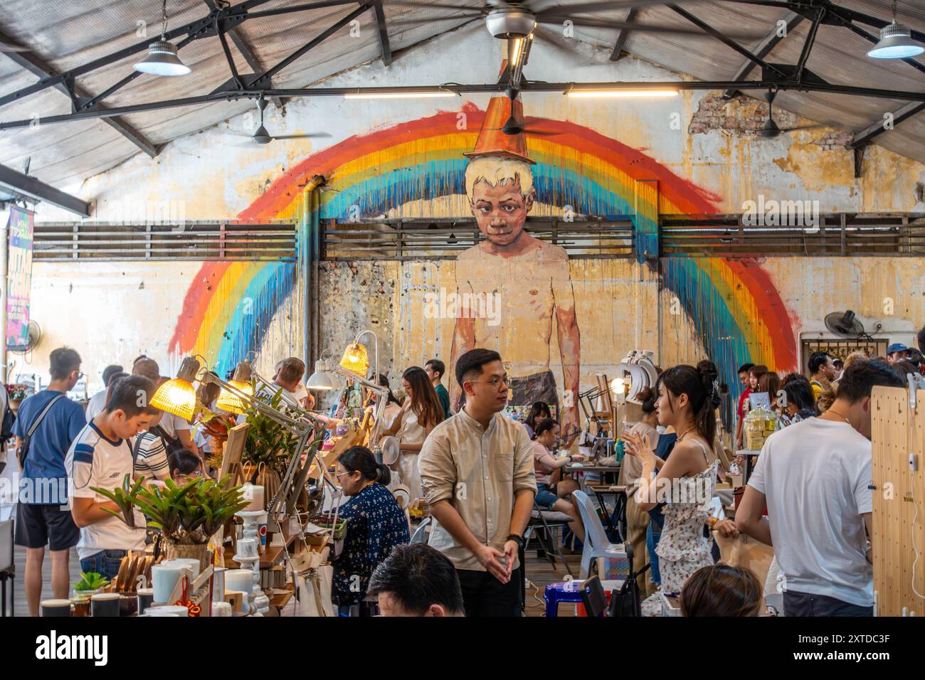 A mural of a boy with a cone on his head looks down on shoppers at the ...