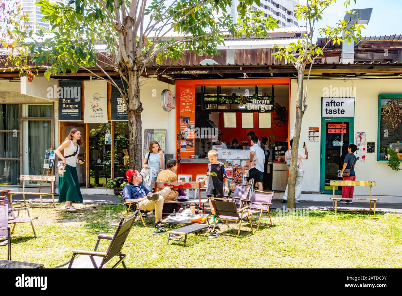People sit and enjoy the sunshine outside a cafe in The Hin Bus Depot ...