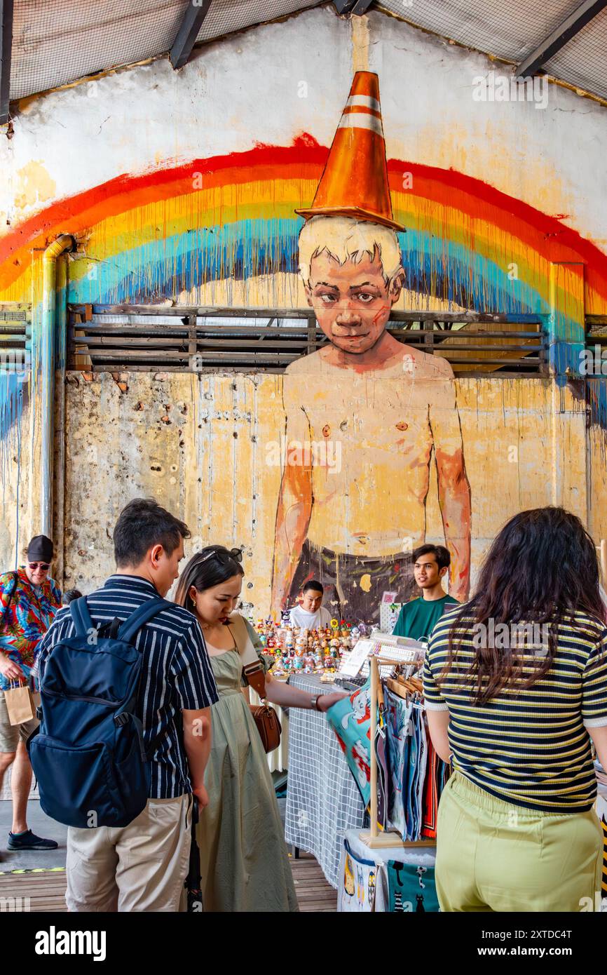 A mural of a boy with a cone on his head looks down on shoppers at the ...