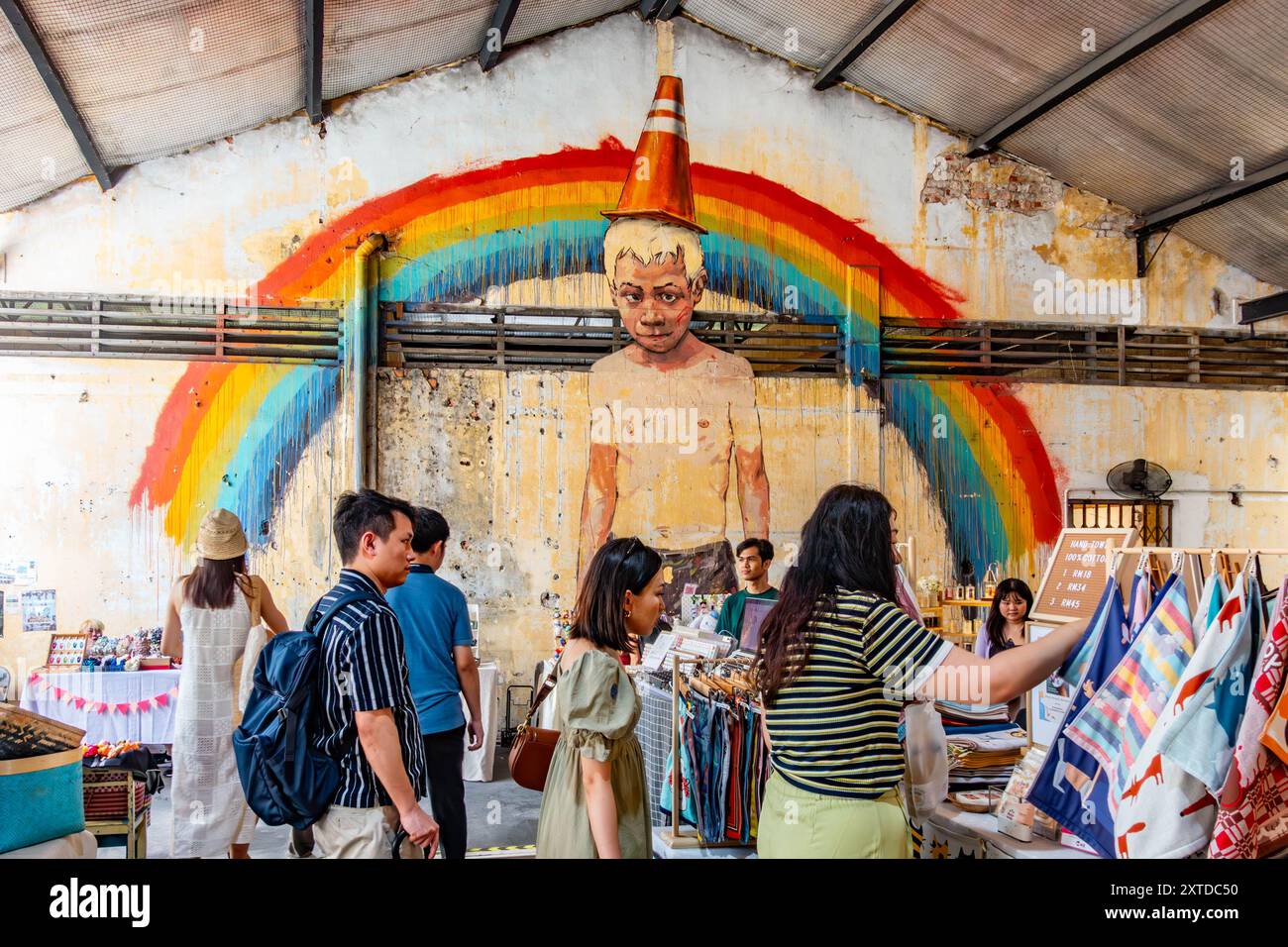 A mural of a boy with a cone on his head looks down on shoppers at the ...