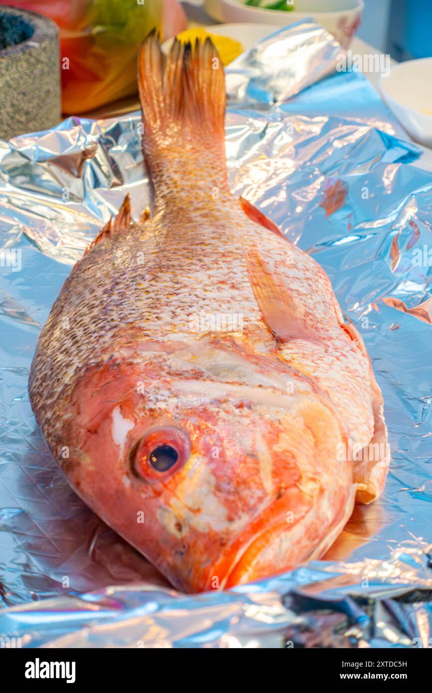 Close up view of a red snapper fish laid out on aluminium foil ready to ...