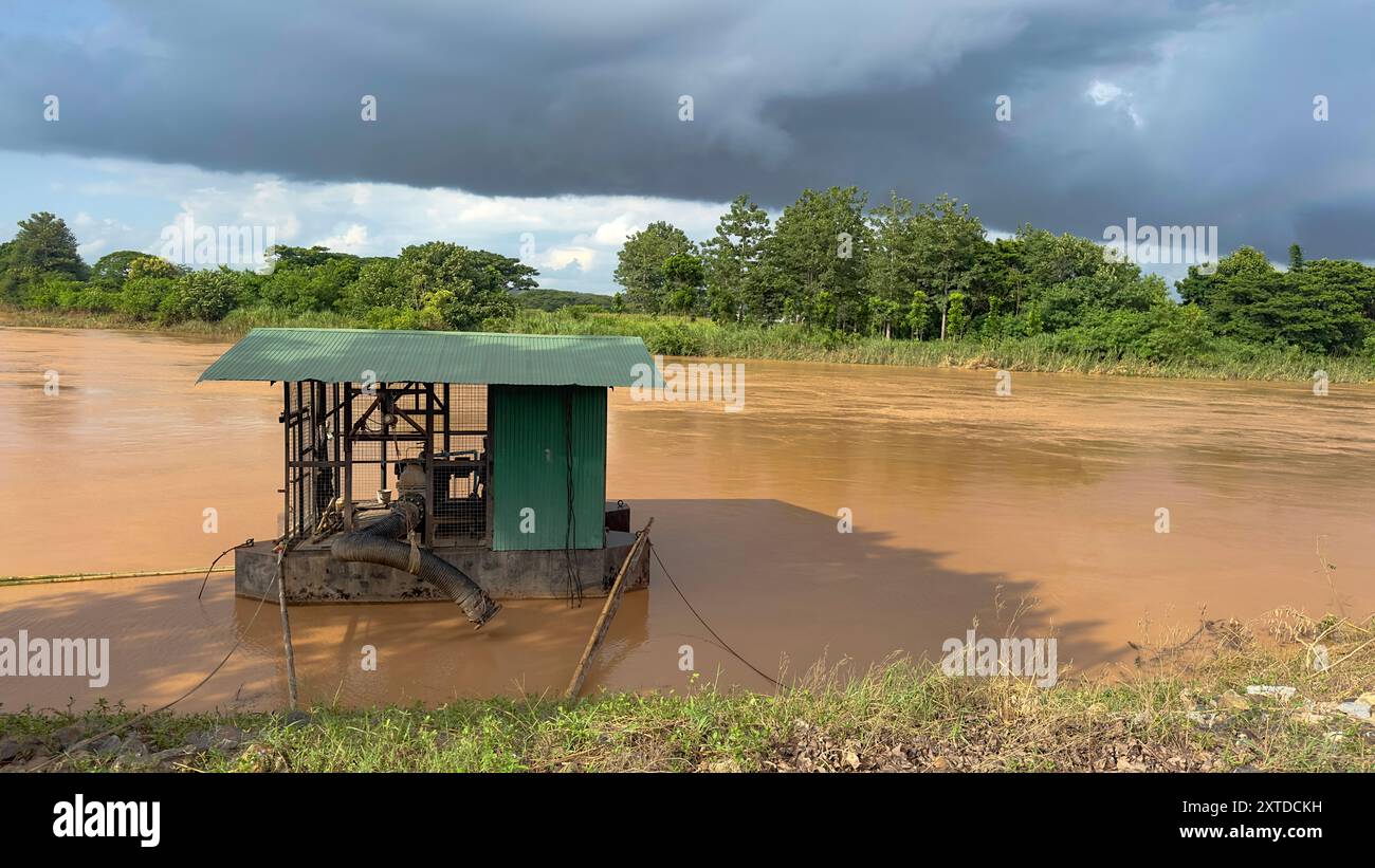 A floating pump station for raw water supply, drifting in a muddy, red ...