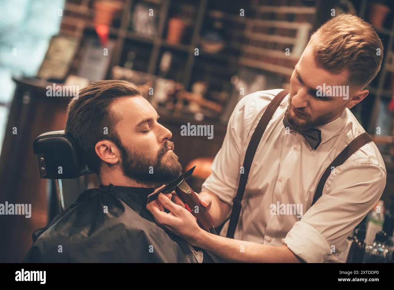 Grooming of real man. Side view of young bearded man getting beard ...