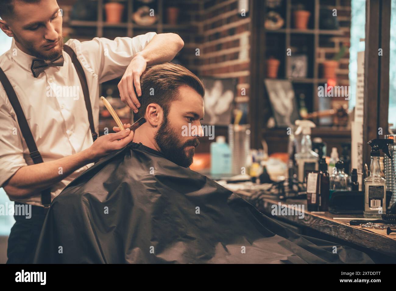 Making hair look magical. Young bearded man getting haircut with ...