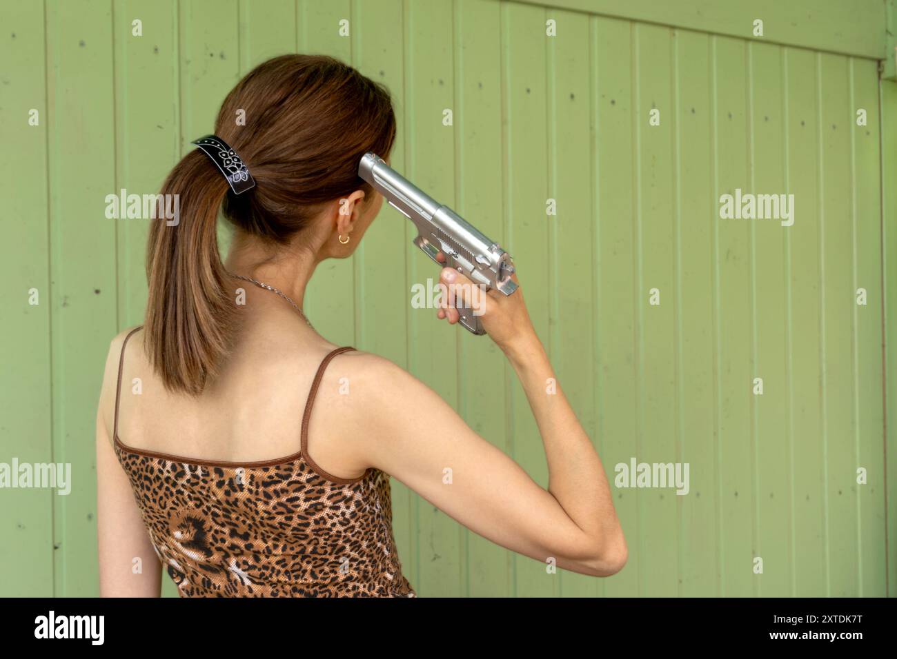 An unrecognizable young woman put toy gun to her temple, showing how ...