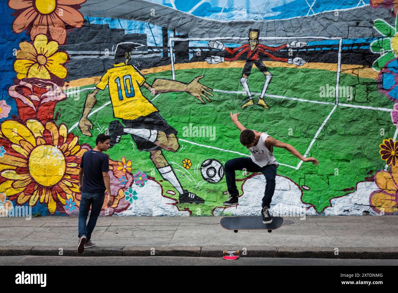 Young skateboarders fly past a football inspired graffiti mural of the ...