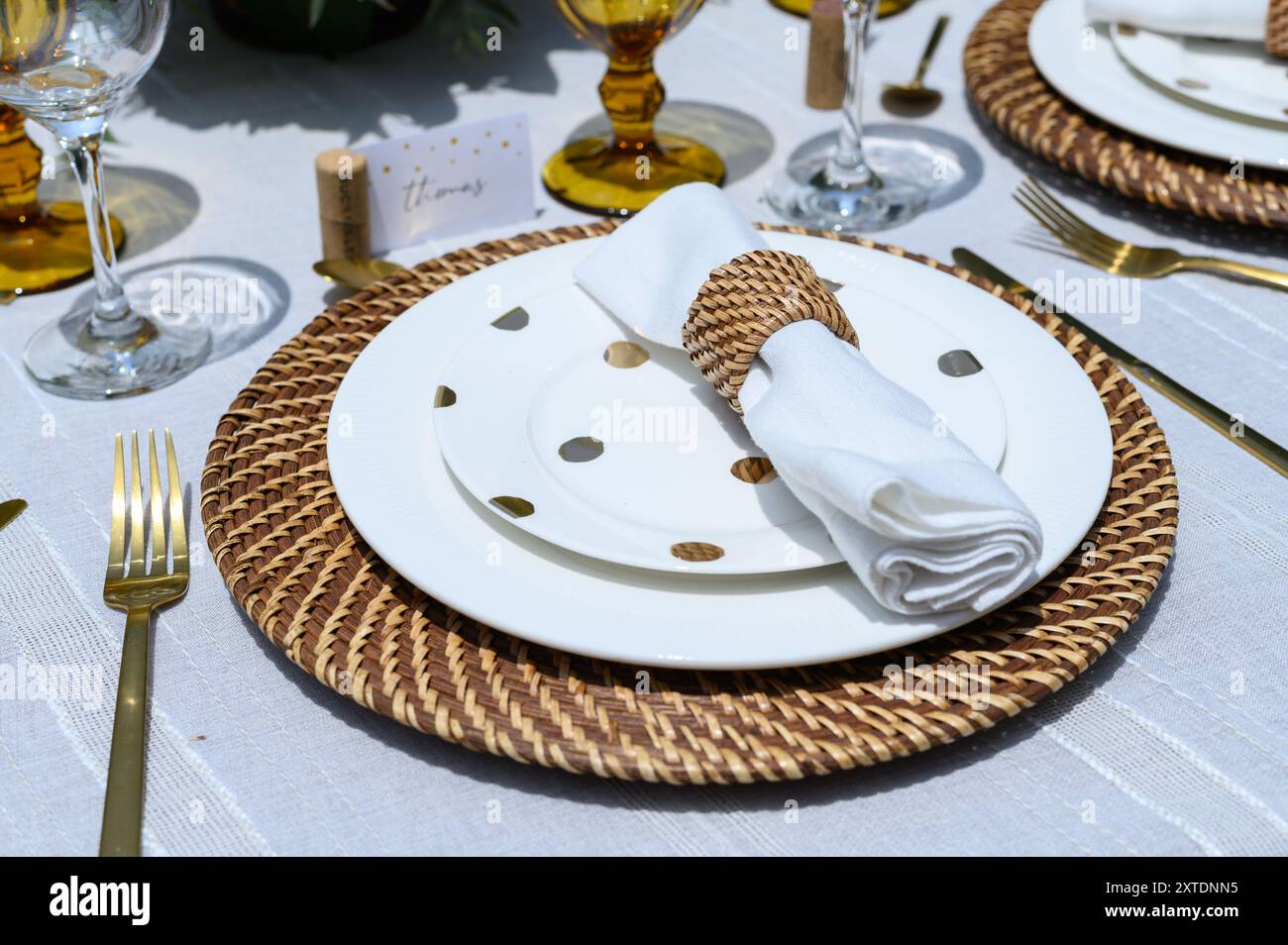 Elegant outdoor dining table setting with white plates and gold cutlery ...