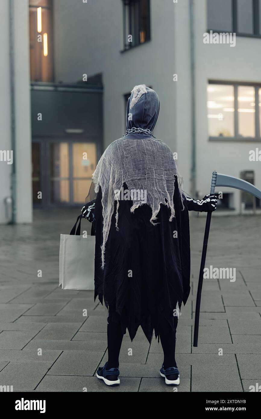 Back view of kid in grim reaper Halloween costume with scythe and bag ...