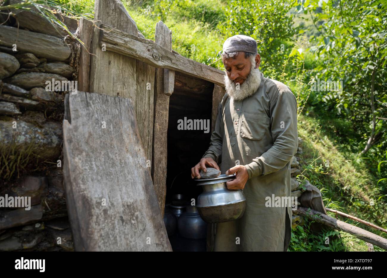 A villager checks a pot full of milk near a cave where milk is ...