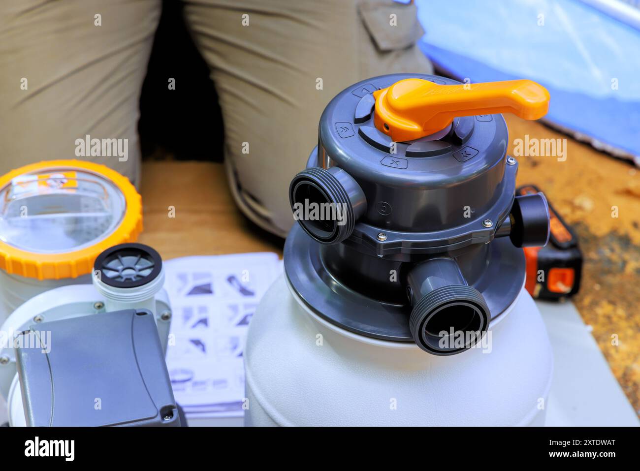 Swimming pool maintenance worker assemble sand filter system tank well ...