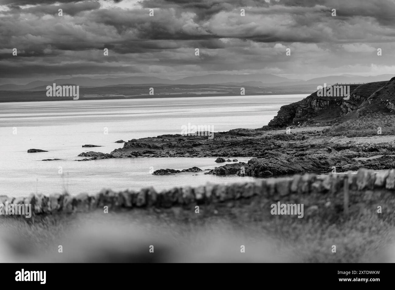 A tranquil coastal landscape features rocky shores and calm waters ...