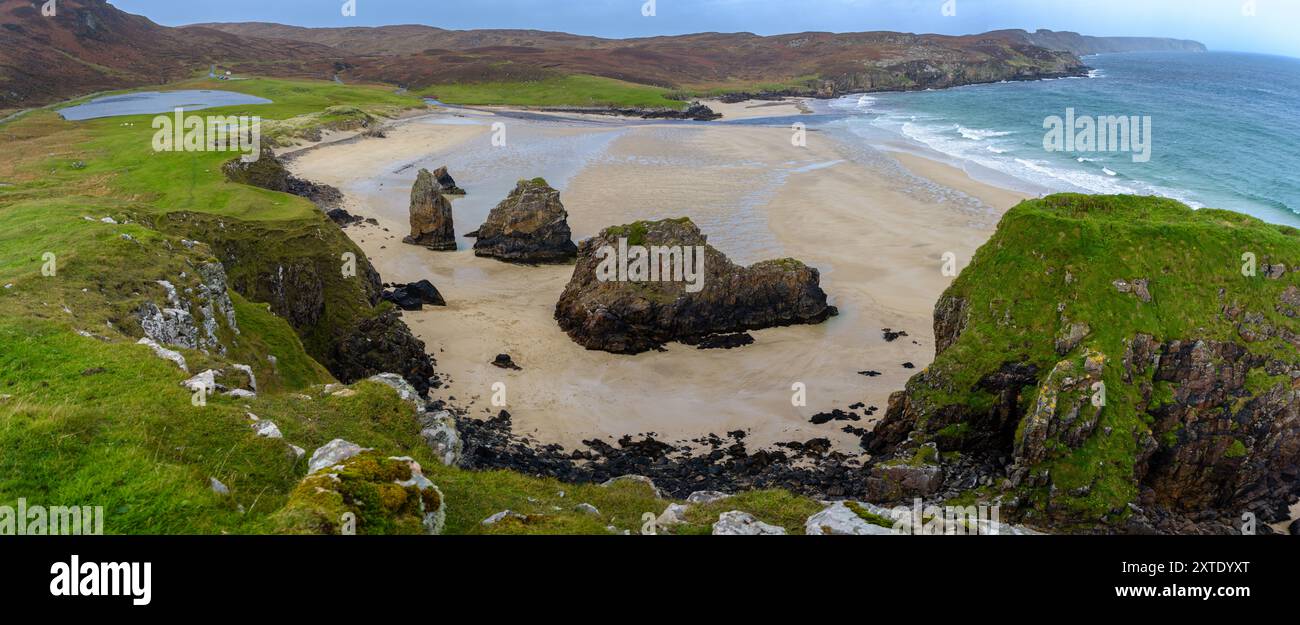Waves gently lap at the sandy shores of Garry Beach, framed by rugged ...