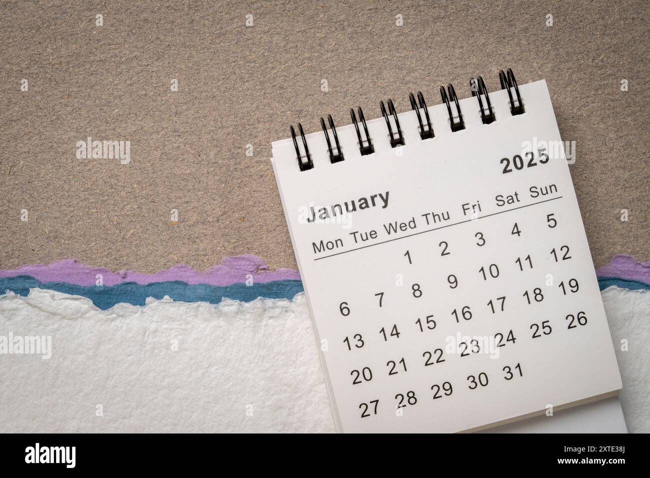 January 2025 - small spiral desktop calendar against abstract paper ...