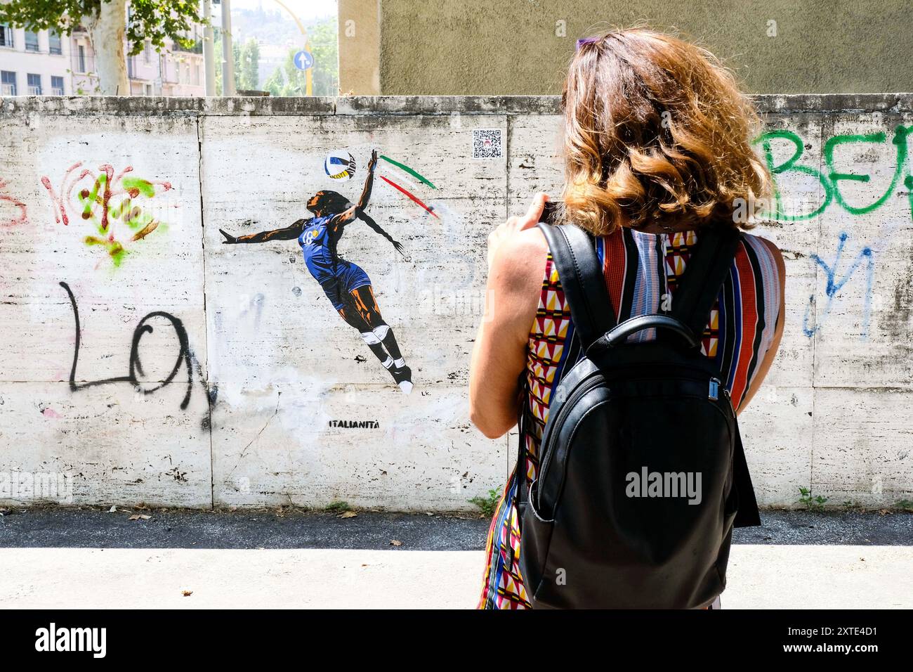 A woman takes a photo of a mural in homage to the Italian volleyball ...