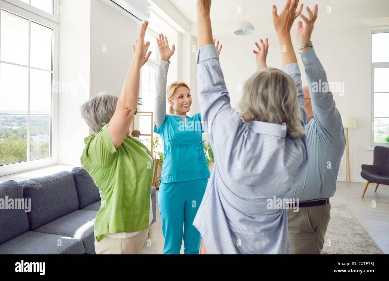 Elderly people and smiling nurse doing physiotherapy exercises with ...