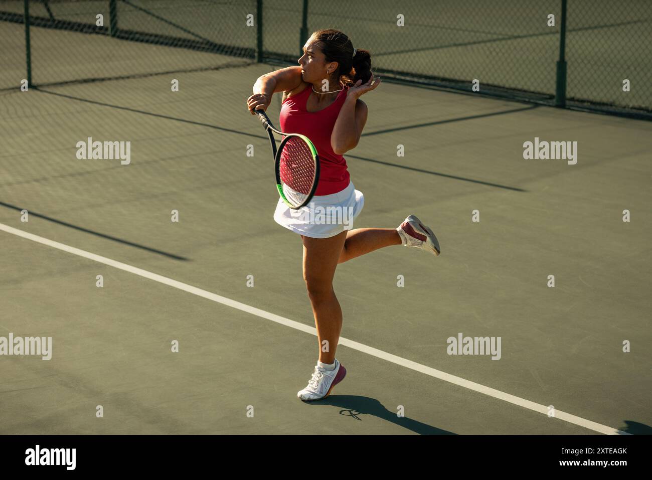 Competitive female tennis player in action hitting a powerful forehand ...