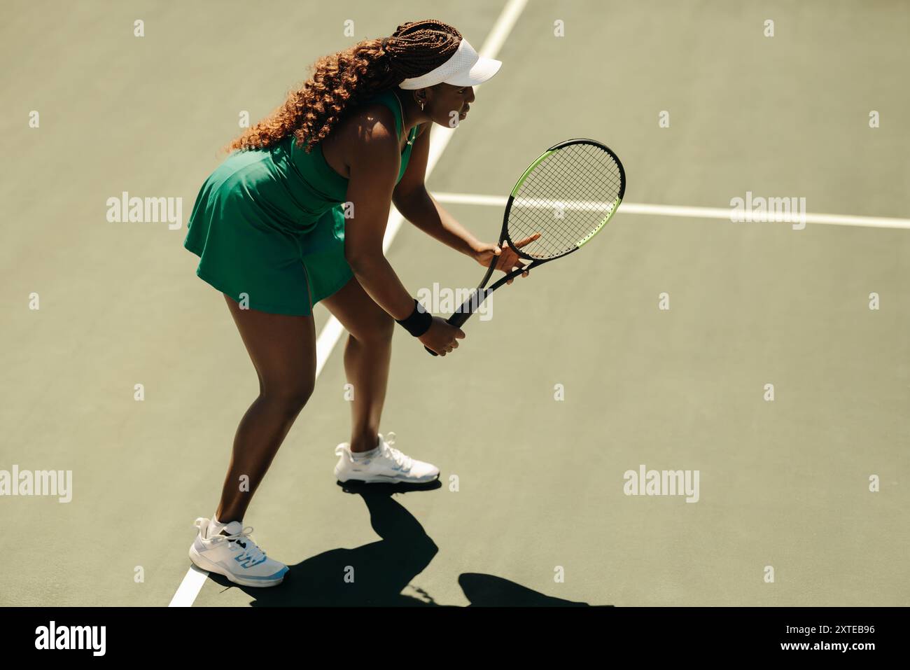 Athletic woman with curly long hair holding a tennis racket, ready for ...