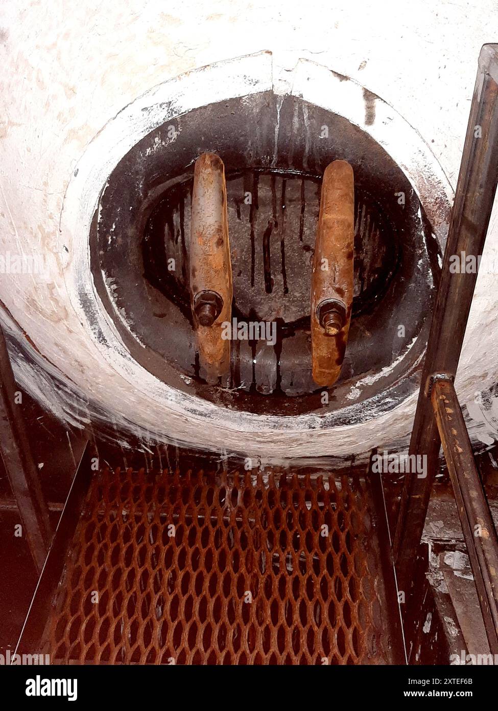The closed drum hatch of an aging steam boiler shows rust and wear ...
