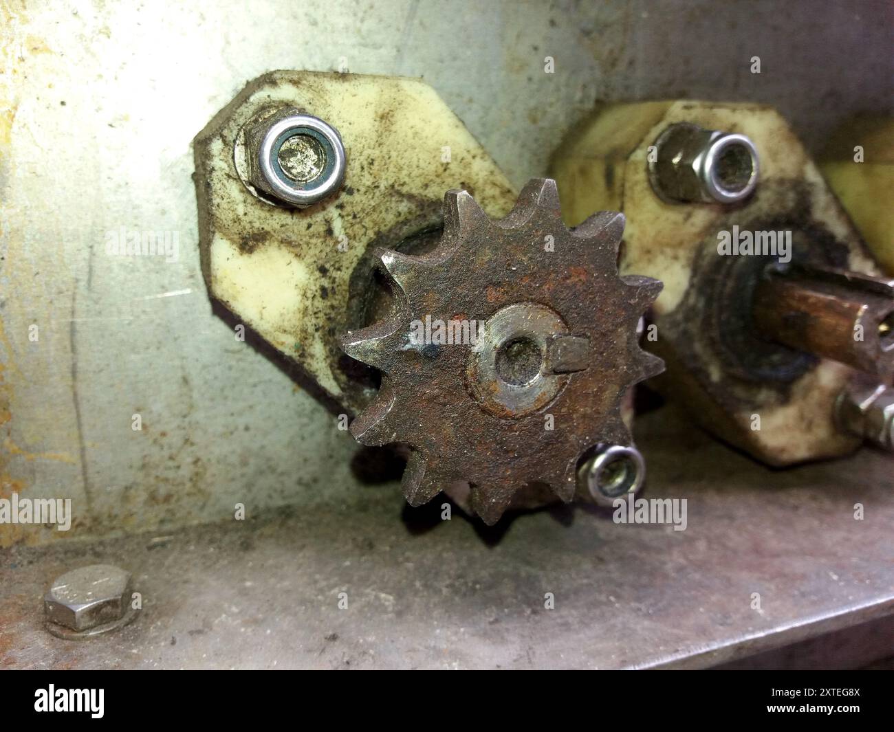 A rusty sprocket from a chain drive mechanism is attached to a metal ...