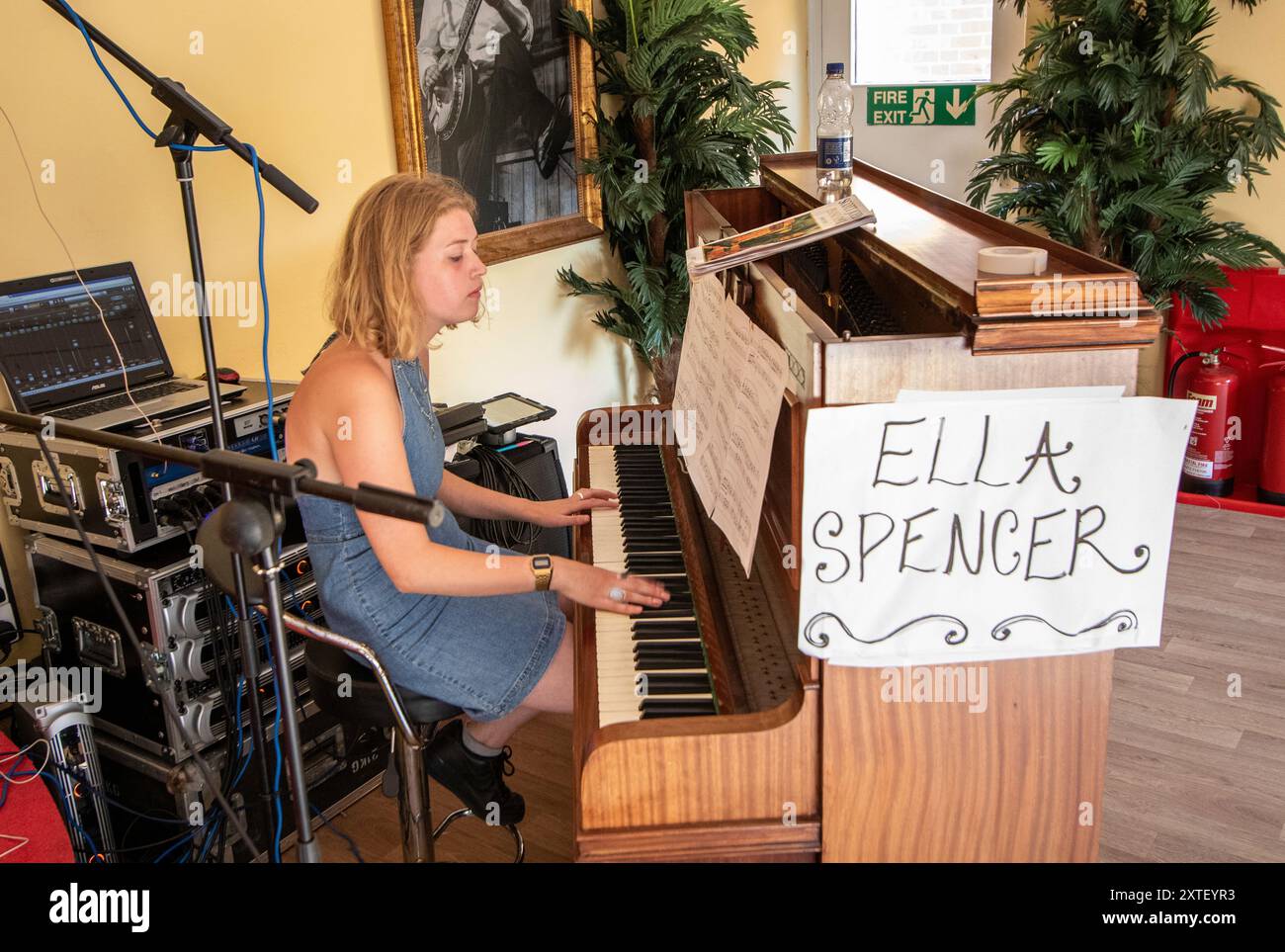 Seated young musician Ella Spencer plays an upright piano in the ...