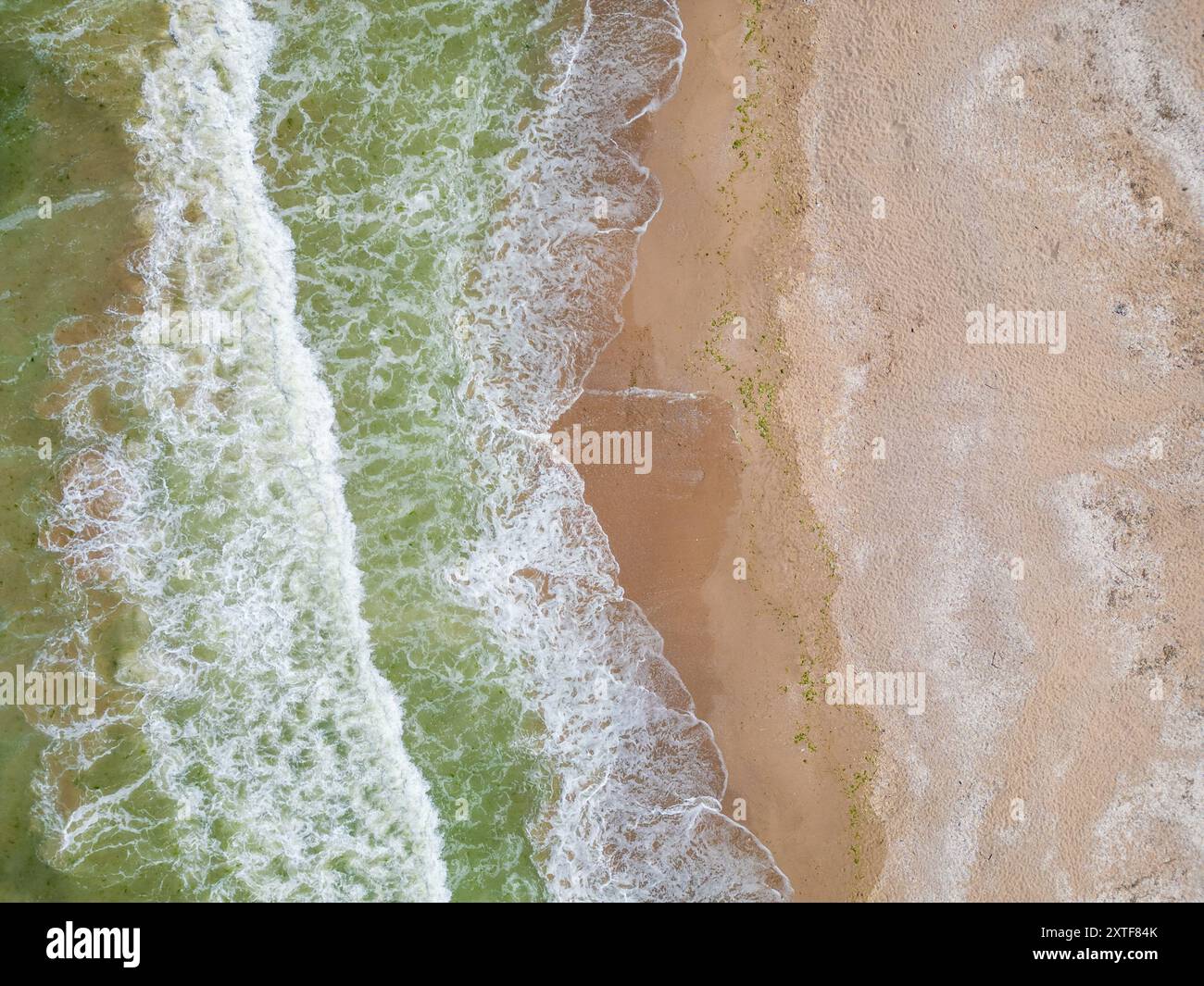 Aerial view of ocean waves crashing onto a sandy beach, creating a ...
