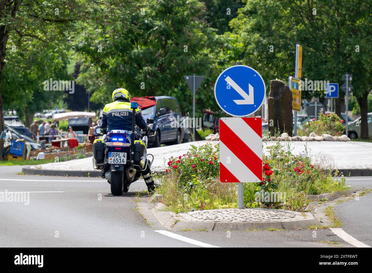 A german police motorcycle with lights flashing is seen on a roundabout ...