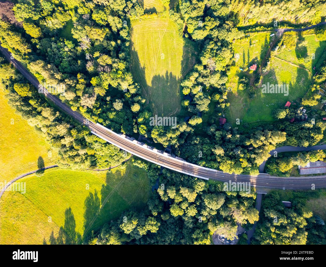 The railway bridge spans through lush greenery, connecting two sections ...