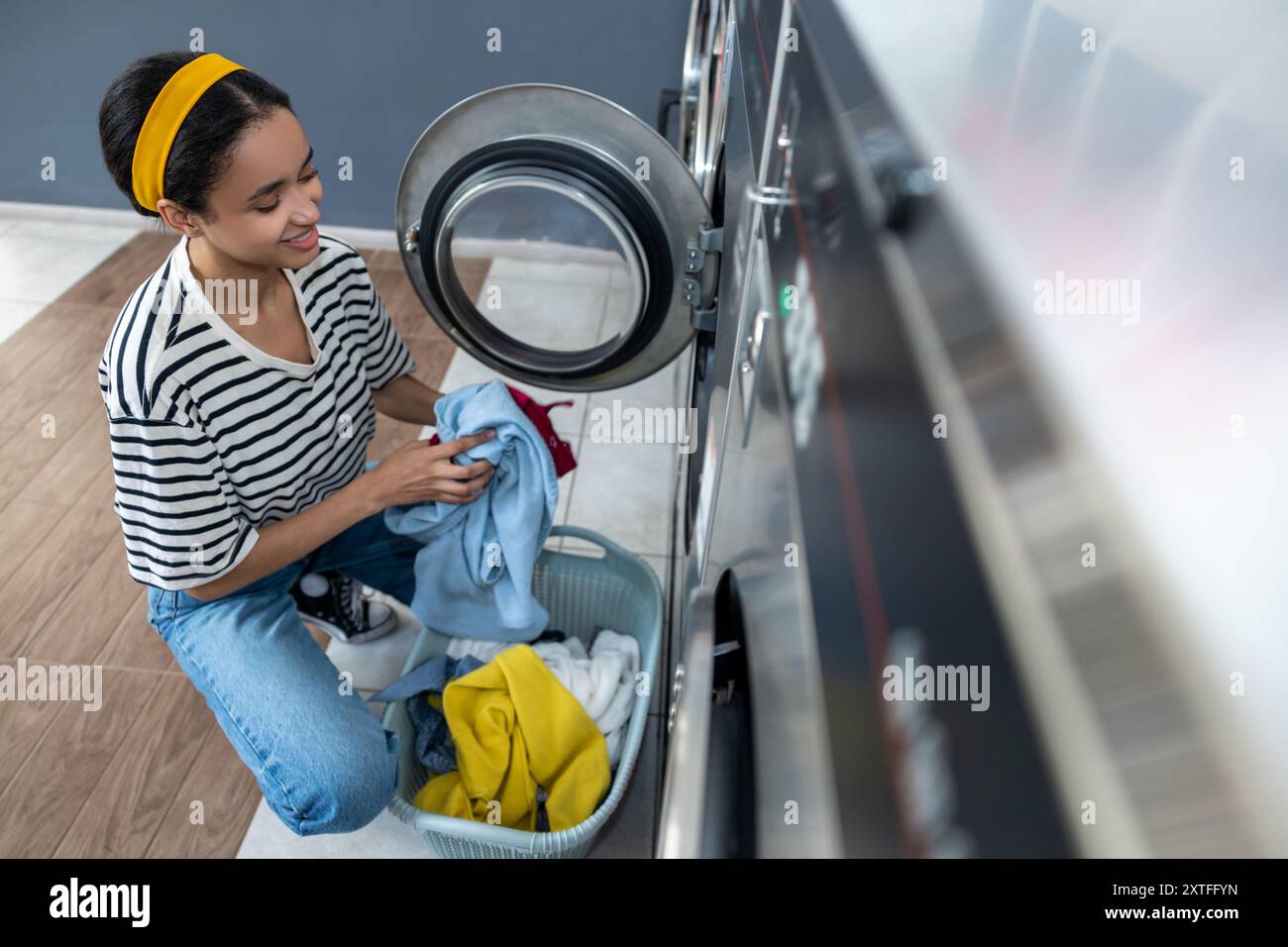 Woman in striped shirt operating laundry appliance at self-service laundry kiosk Stock Photo - Alamy