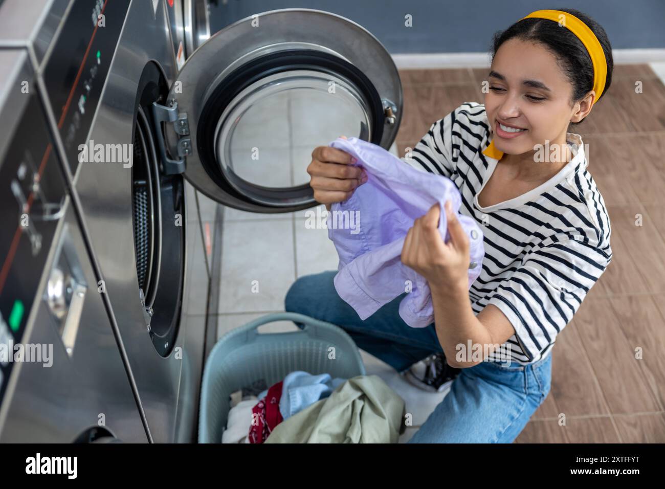 Smiling woman managing household chores at public laundry Stock Photo ...