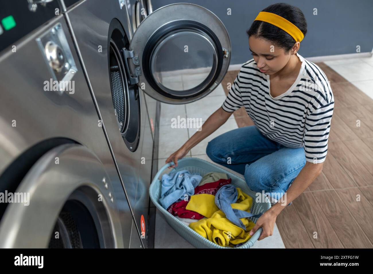 Brunette woman cleaning clothes at industrial laundromat Stock Photo ...