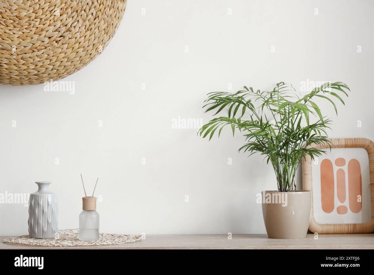 Aroma diffuser, vase, frame and houseplant on chest of drawers in ...