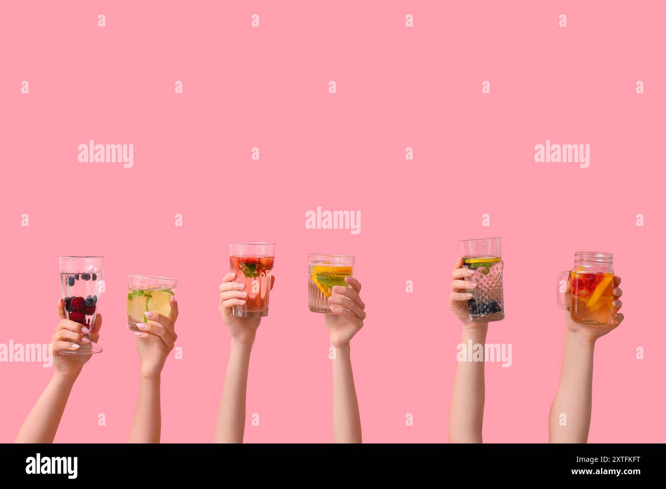 Many hands with infused water on pink background Stock Photo - Alamy