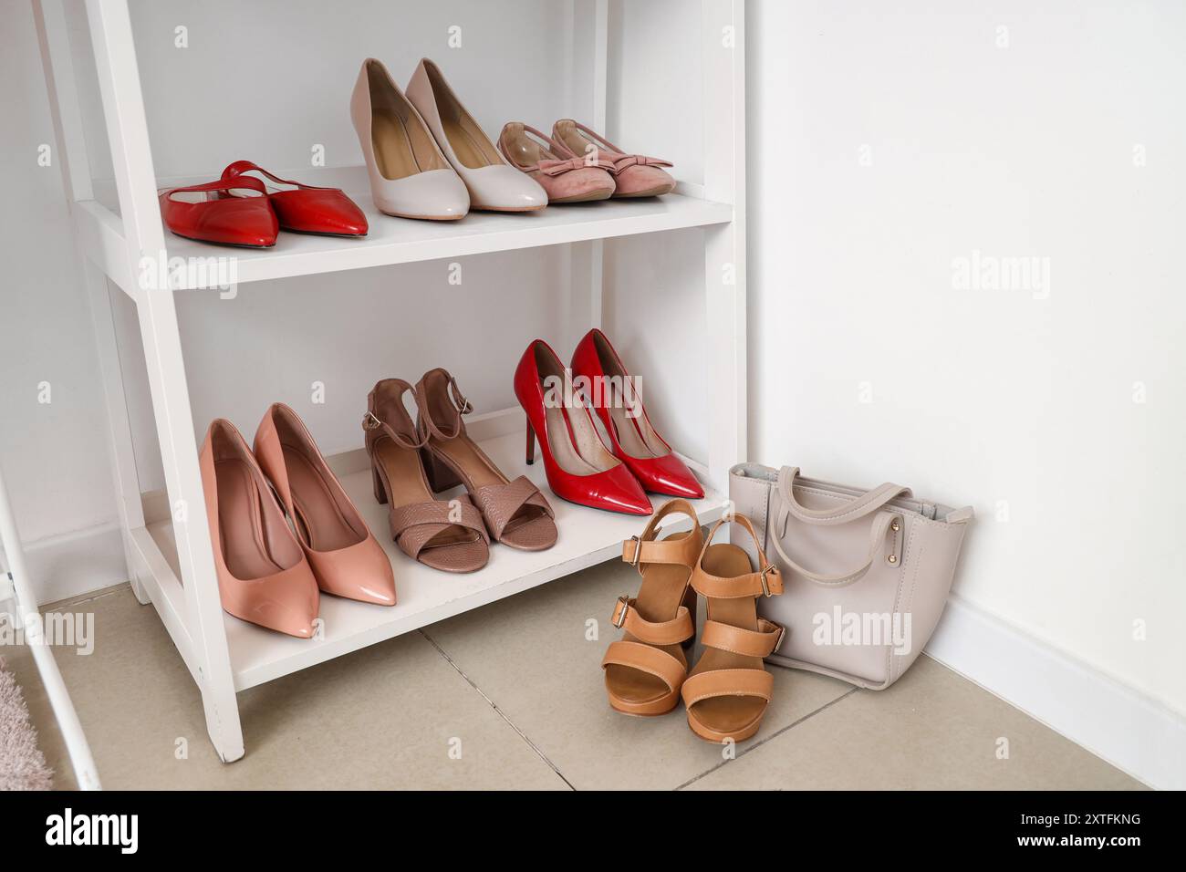 Shelving unit with different stylish female shoes near white wall in ...