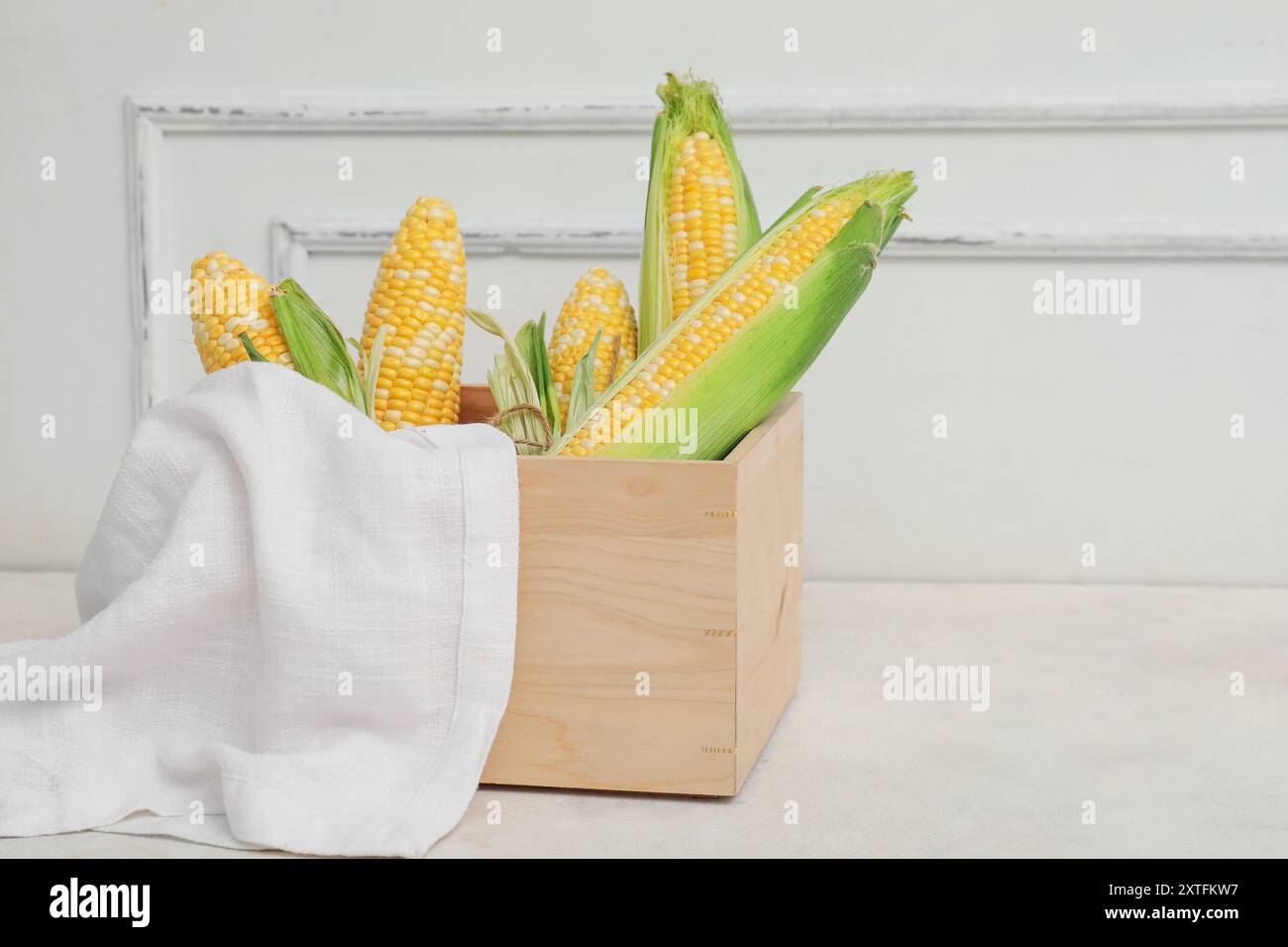 Wooden box with fresh corn cobs and napkin on light background Stock ...