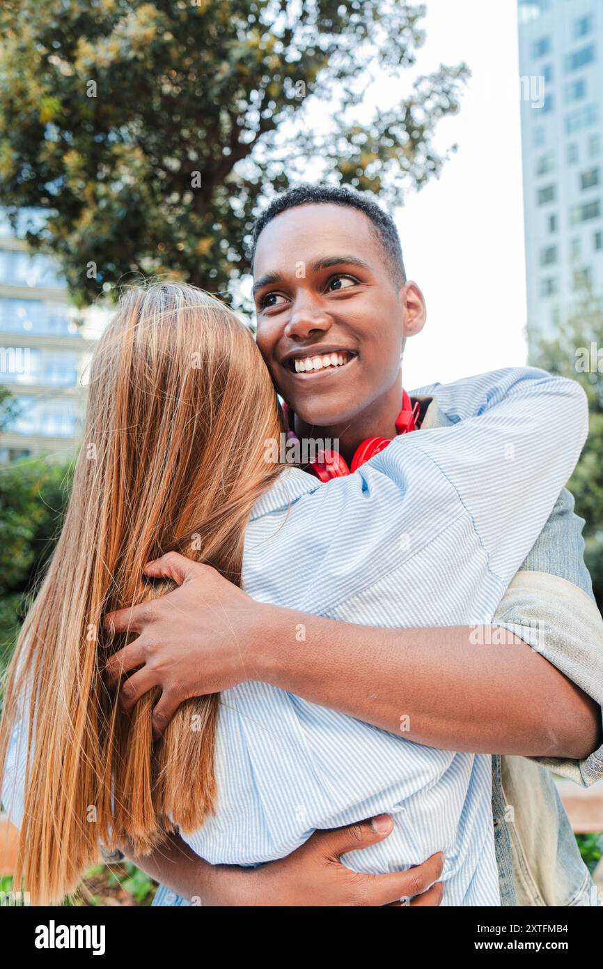 Vertical. African American man giving a tender hug to his girlfriend ...
